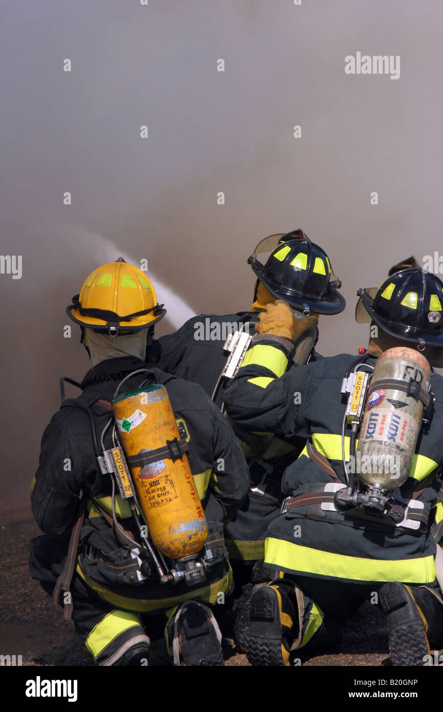 Three fire fighters putting out a fire Stock Photo - Alamy