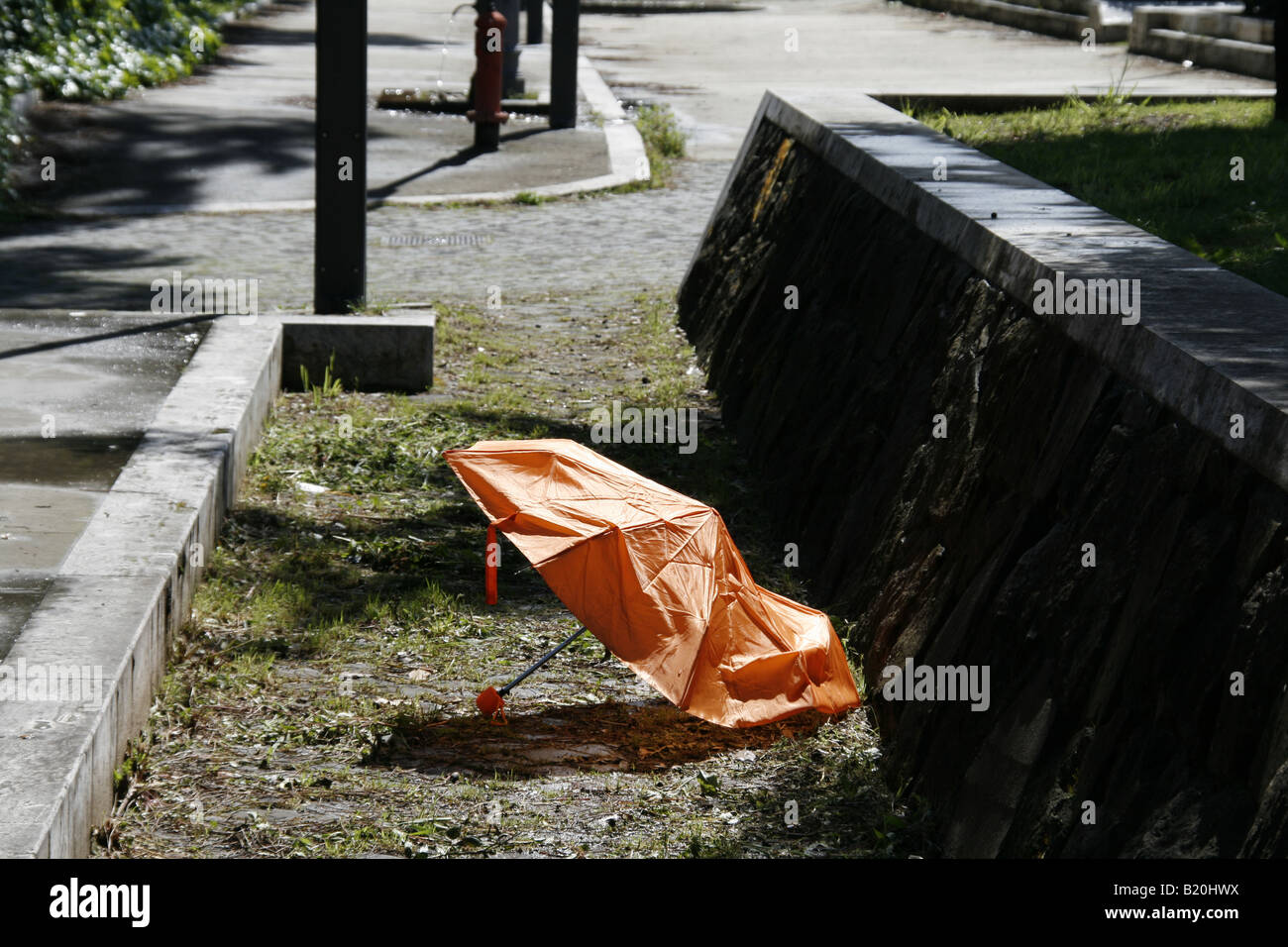 old orange umbrella left on pavement in town Stock Photo - Alamy