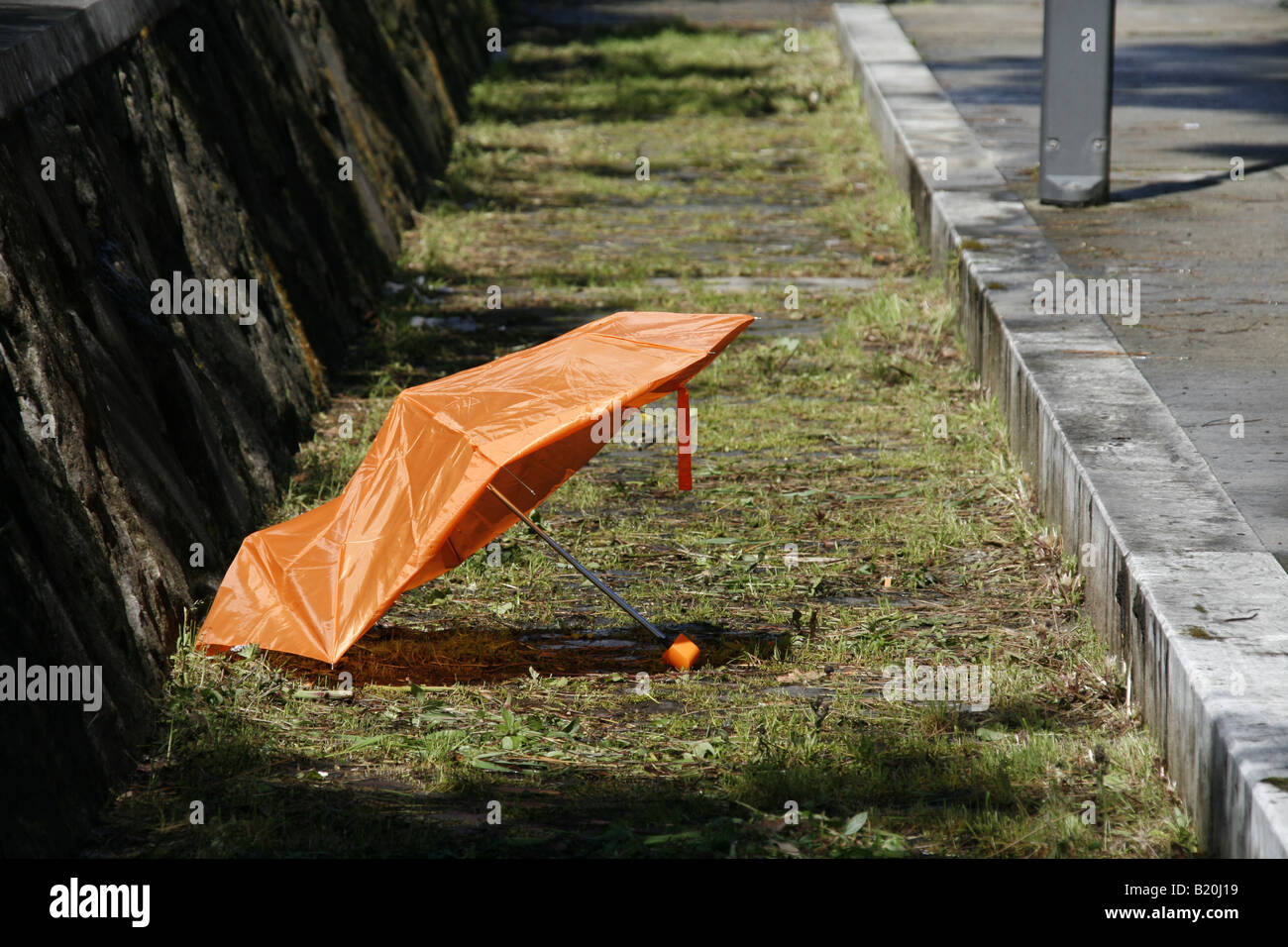 old orange umbrella left on pavement in town Stock Photo - Alamy