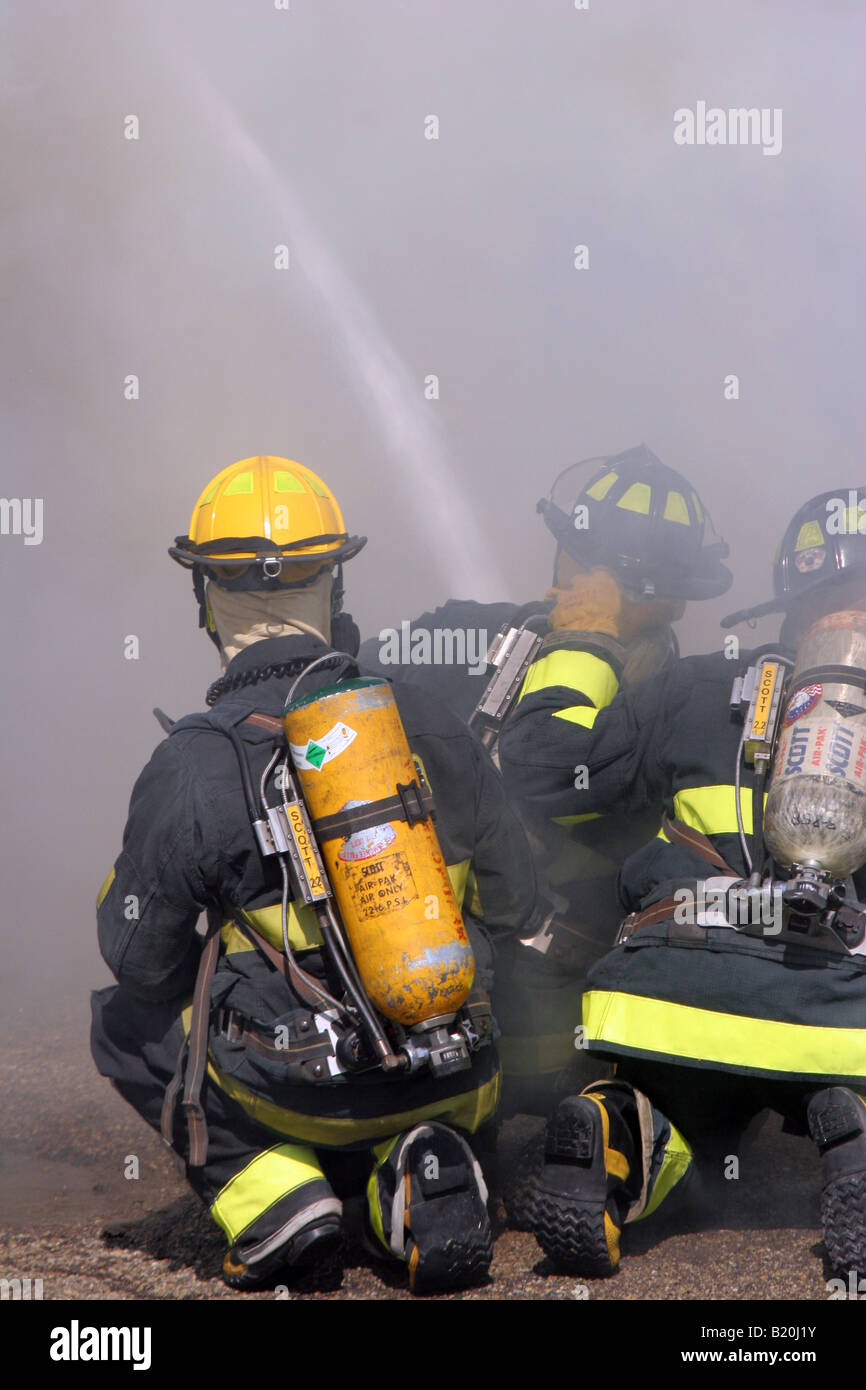 Three fire fighters putting out a fire Stock Photo - Alamy