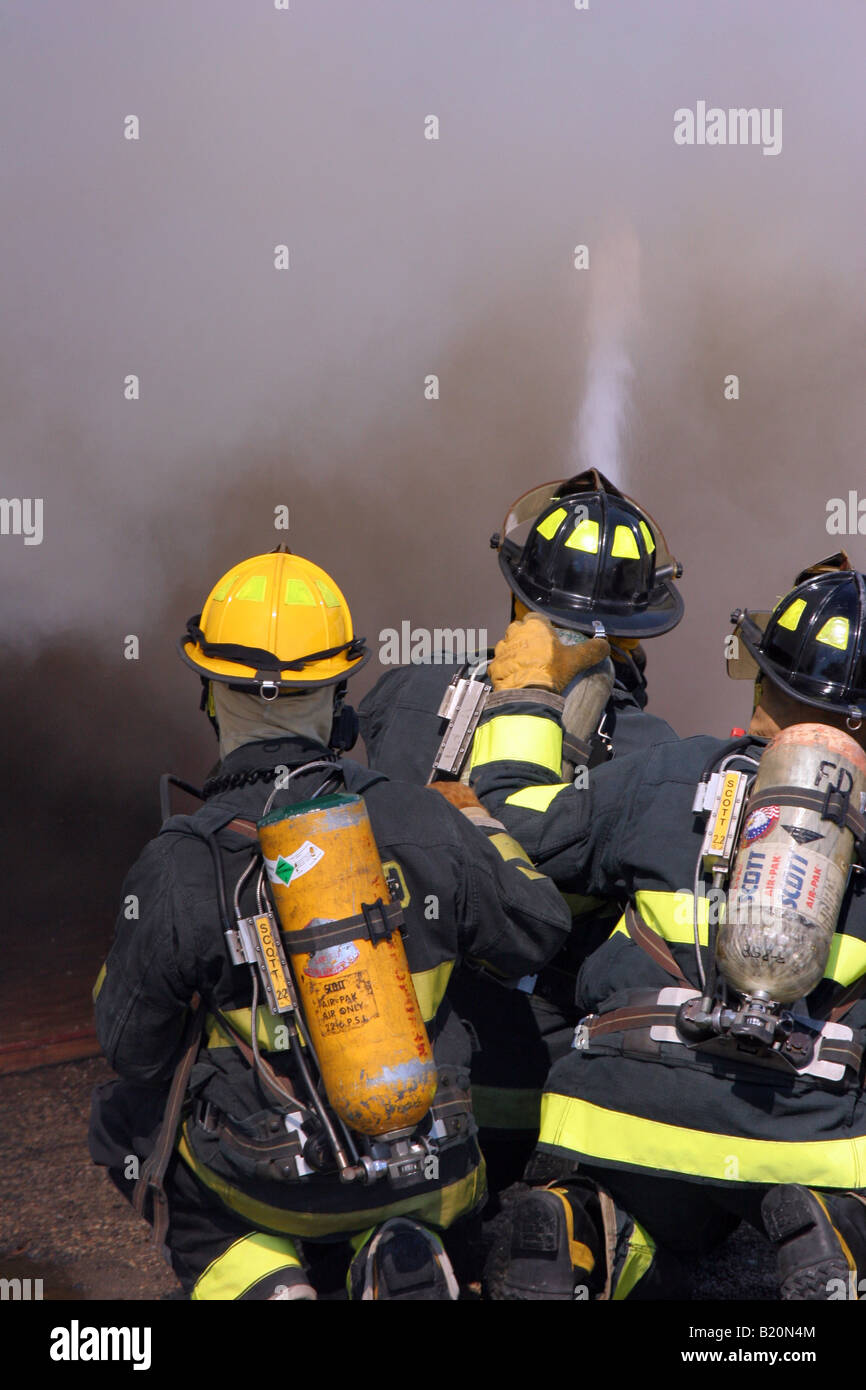 Three fire fighters putting out a fire Stock Photo - Alamy