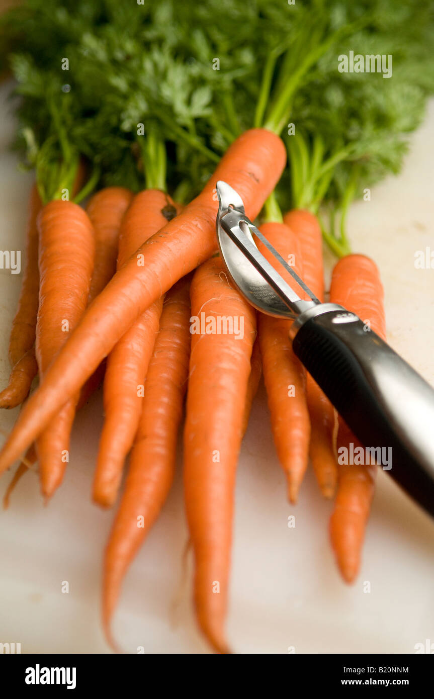 Fresh cleaned carrots sitting on a cutting board with a vegetable ...