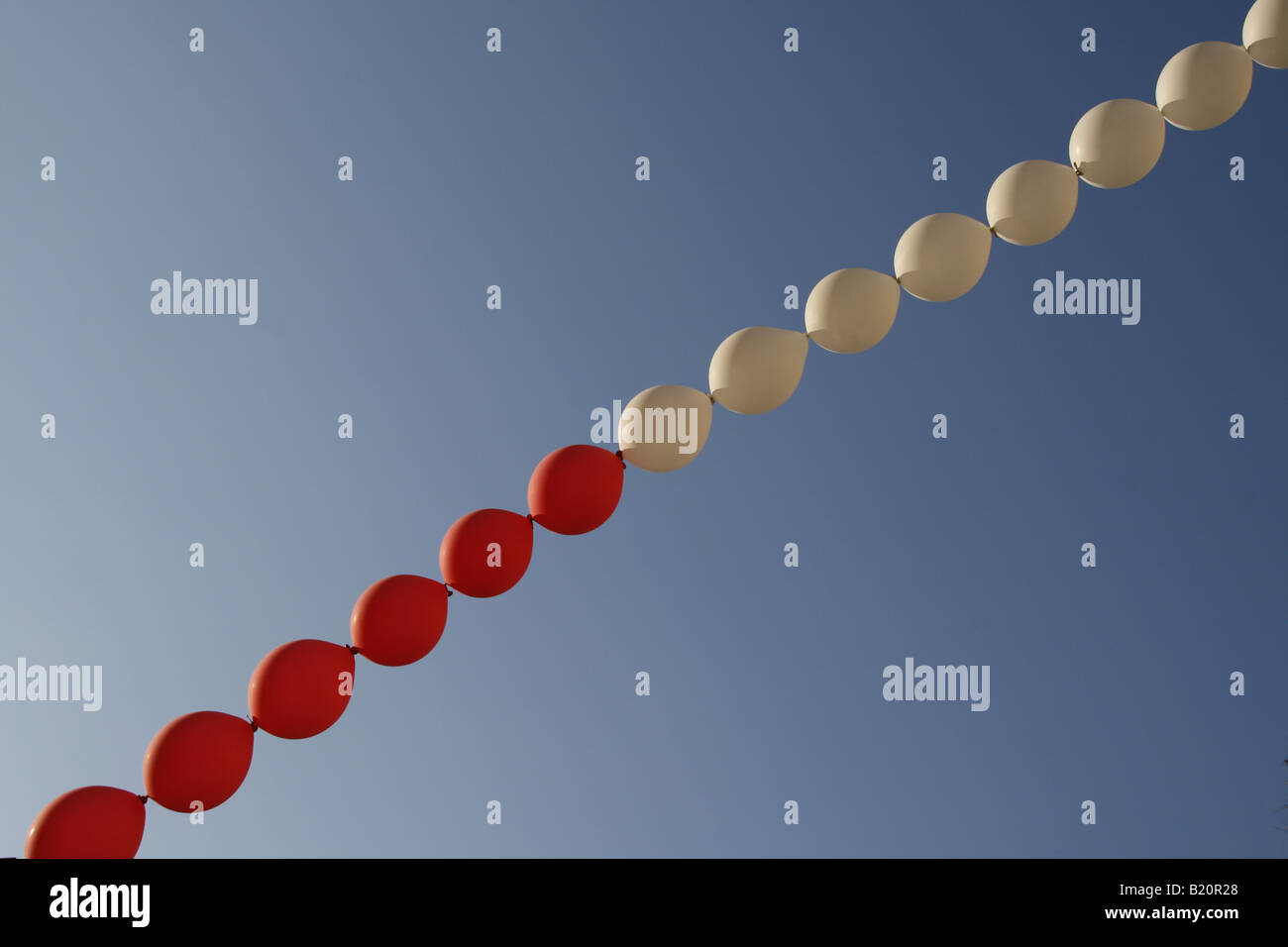 long line of red white balloons in blue sky Stock Photo - Alamy