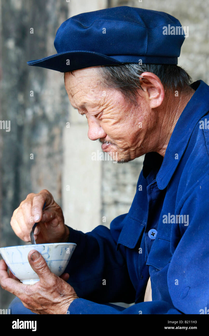 Chinese man eating breakfast at the village of Tuanshan, Yunnan, China ...