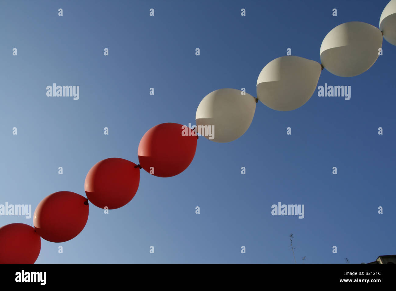 long line of red white balloons in blue sky Stock Photo - Alamy
