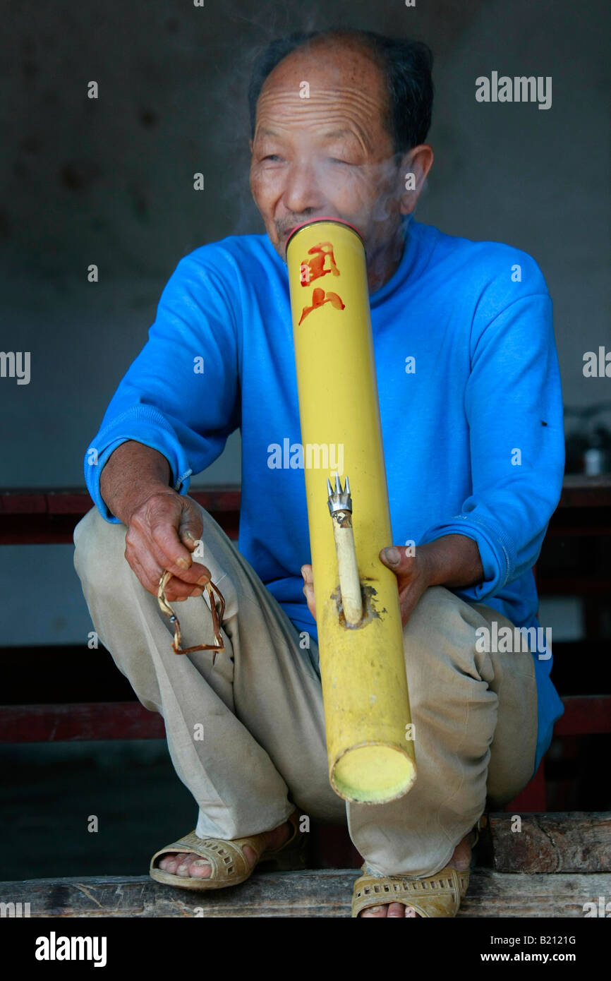 Chinese man smoking a traditional pipe at the village of Tuanshan ...