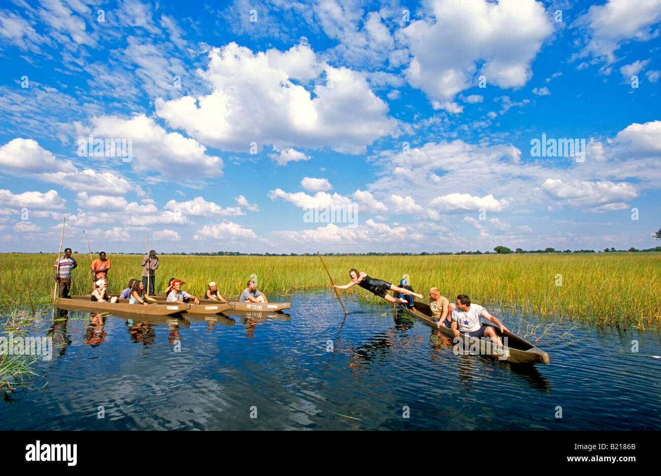Tourists on a Mokoro boat trip in the Okavango Delta with one trying to ...