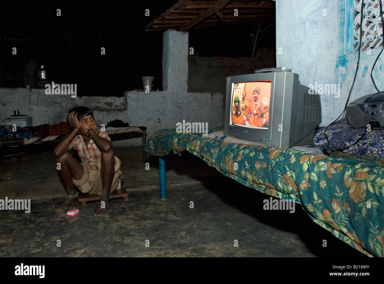 Rajasthani child watching a traditional television programme on a tv ...