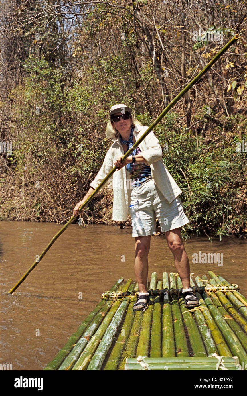 Active senior woman (50-60 years) poles bamboo raft in northern ...