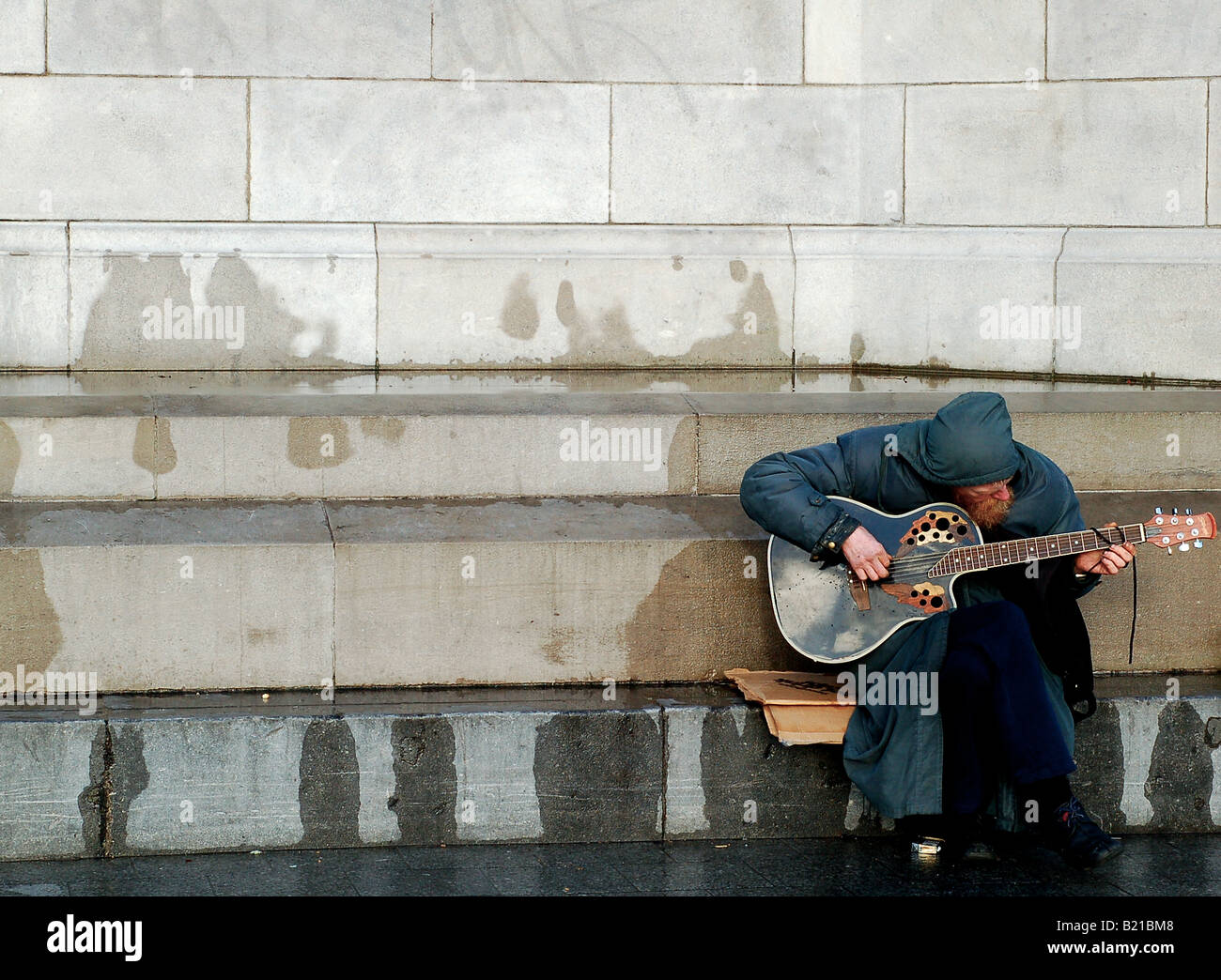 A homeless man sits playing music to passers by on the streets in ...