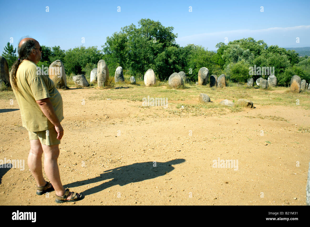 Man looking at Almendres Cromlech stone circle near Guadalupe, Evora ...