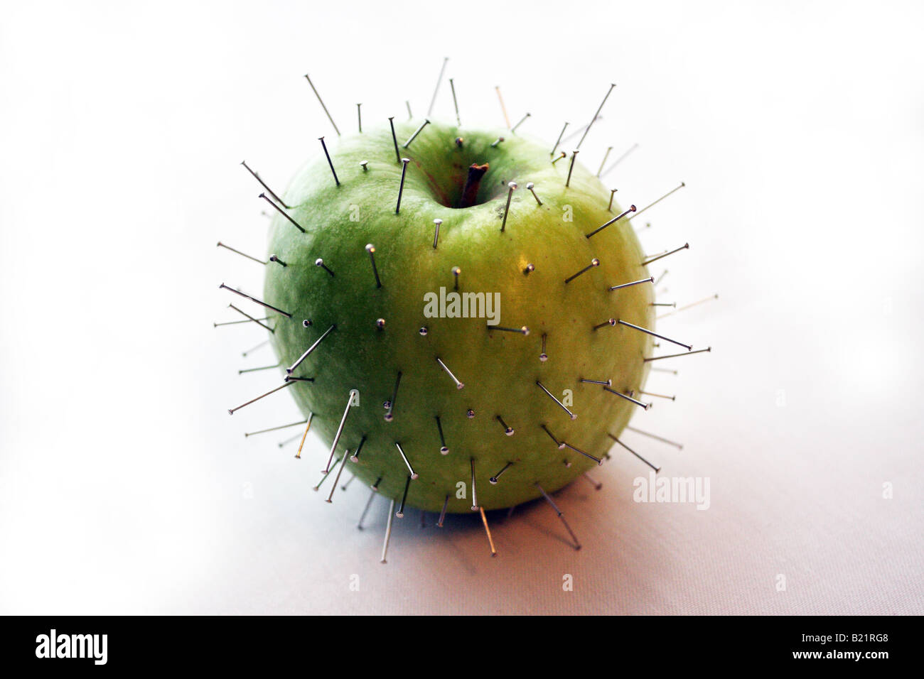 A green apple with pins embedded in to it Stock Photo - Alamy