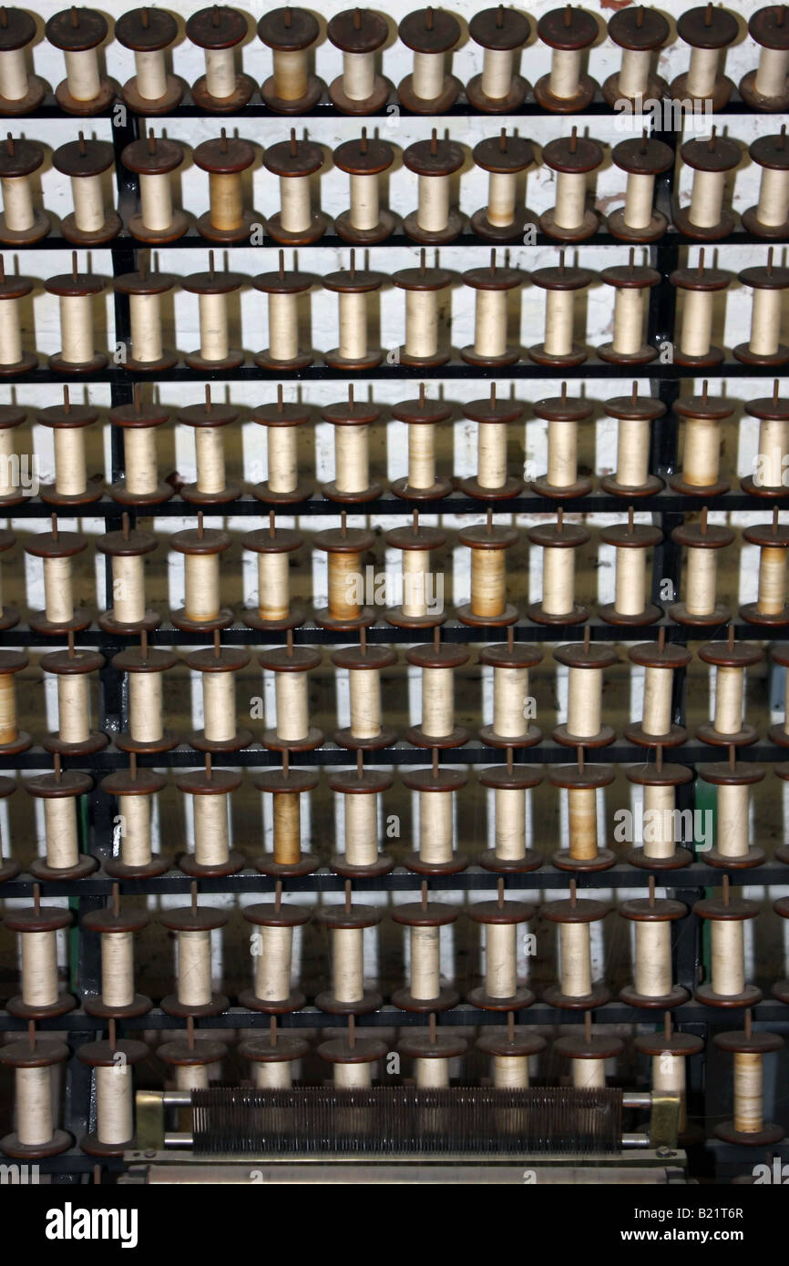 A close up photograph of a textile machine bobbins at a lace making ...