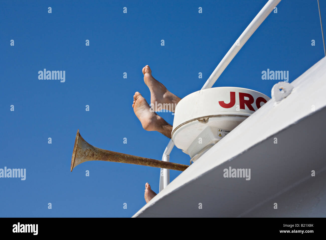 Legs resting on boat railing Stock Photo - Alamy