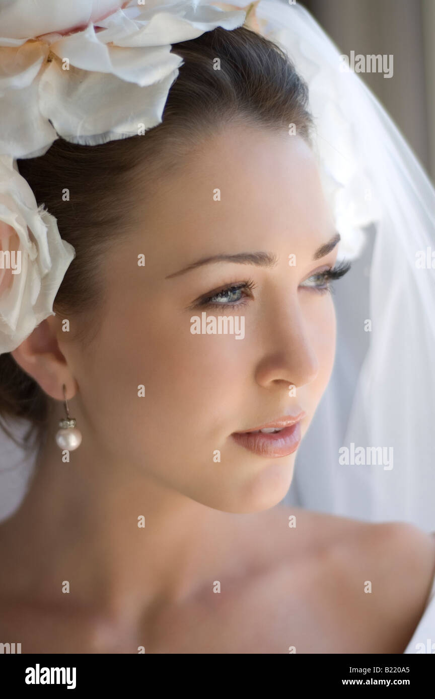 A headshot of a beautiful bride with a pink floral headdress and veil ...