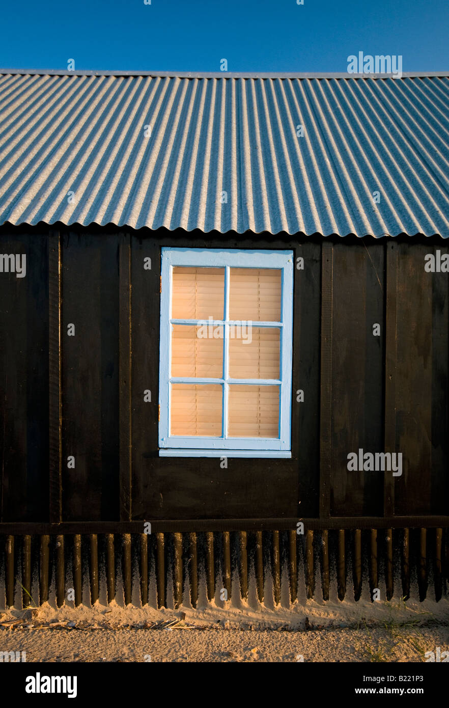Side view of a black and light blue beach hut lit by low sunlight Stock ...
