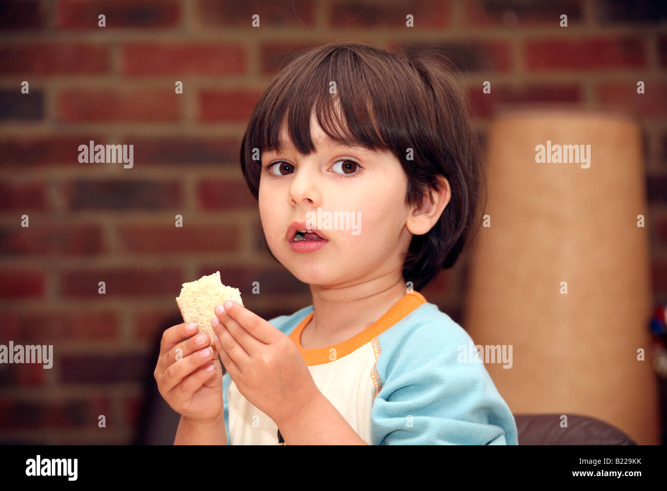 Portrait of surprised brunette boy eating bread Stock Photo - Alamy
