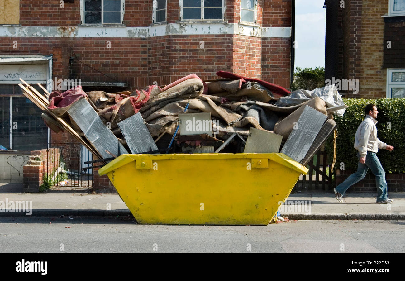 Overloaded skip on a street in south London Stock Photo - Alamy