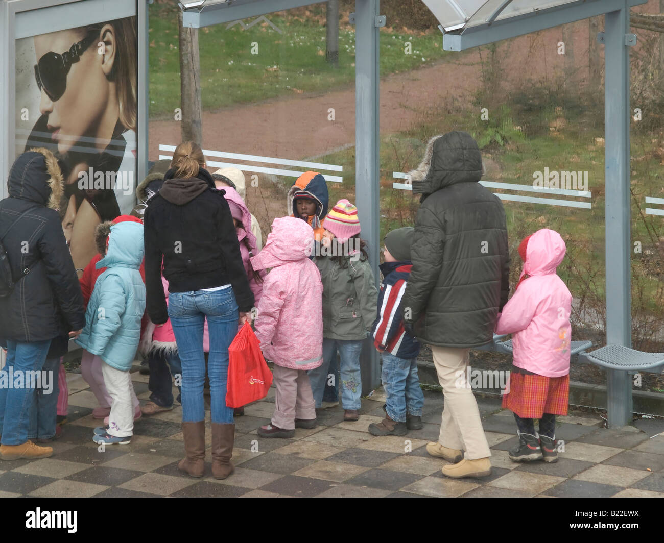 groupe of children standing at bus stop waiting for the bus in ...