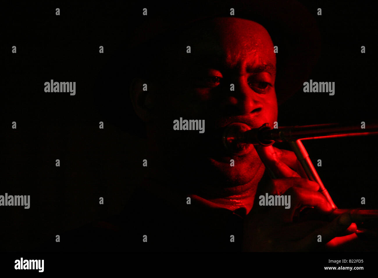 Dramatically side lit in red portrait of a black musician playing the ...