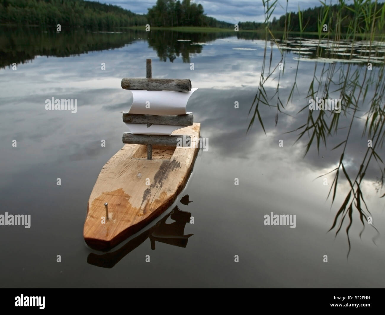 a little sailing ship handmade on lake with water lilies and reeds ...