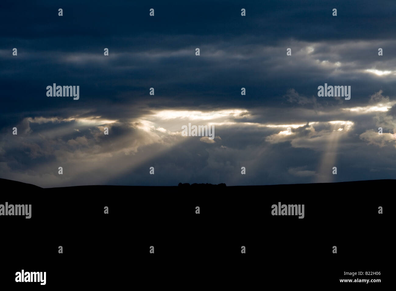Sun rays streaking through stormy clouds illuminating the top of the ...