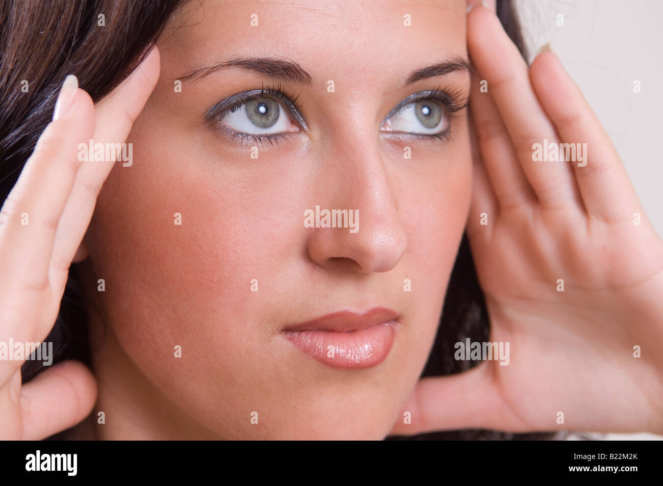Beautiful young woman with blue eyes hands on face looking up Stock ...