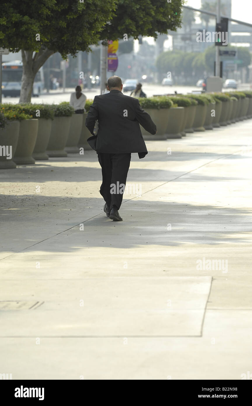 Businessman in a suit hurriedly walking down a sidewalk. View from ...
