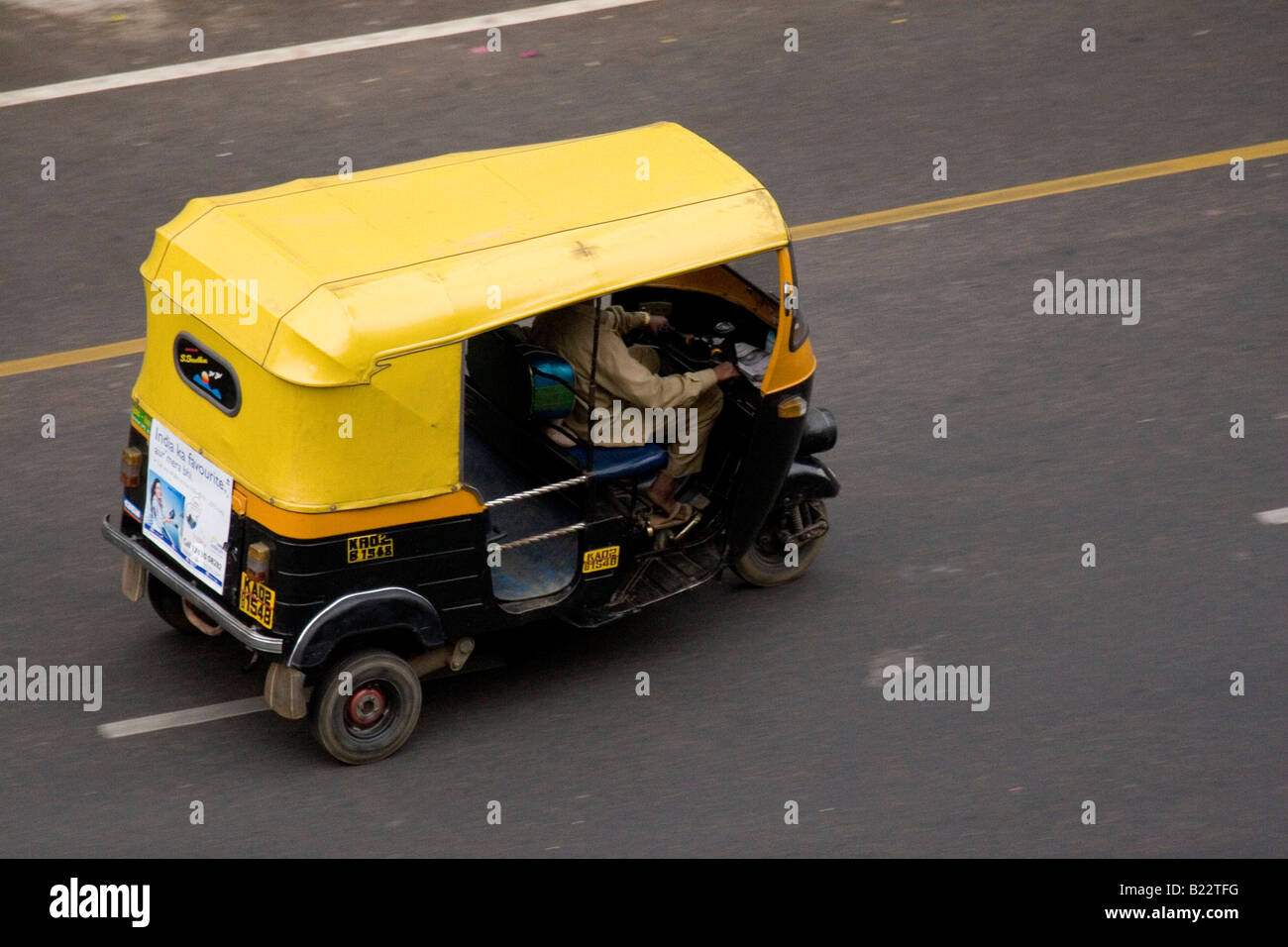 A rickshaw drives on a road in Bangalore, South India. The rickshaw is ...