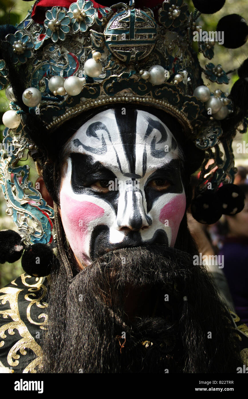 A male member of a Chinese opera company stands made up and ready to ...