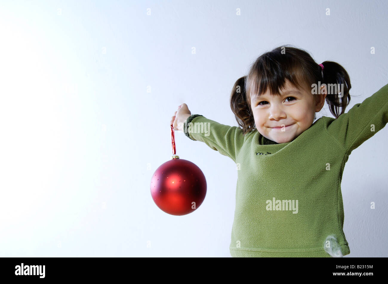 Portrait of girl holding christmas bauble and smiling Stock Photo - Alamy