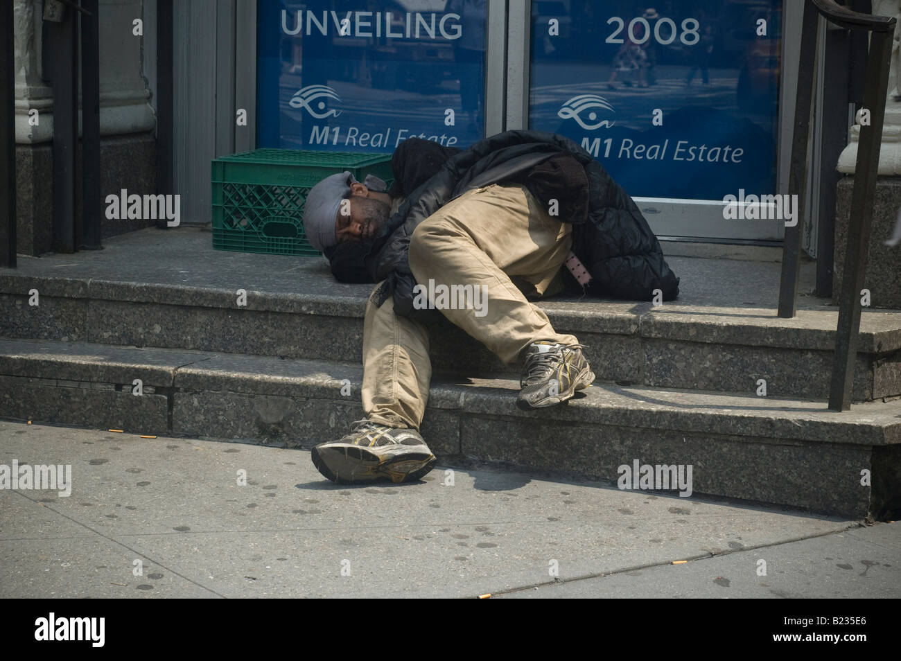 A homeless man sleeps on the steps of a building in Midtown Manhattan ...
