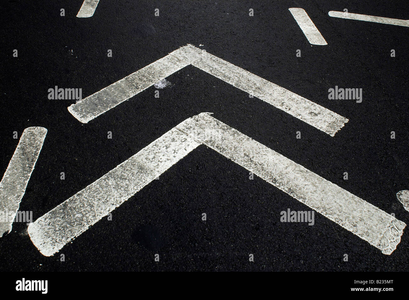 Close up of white thermal lane markings in the shape of a V on a black ...