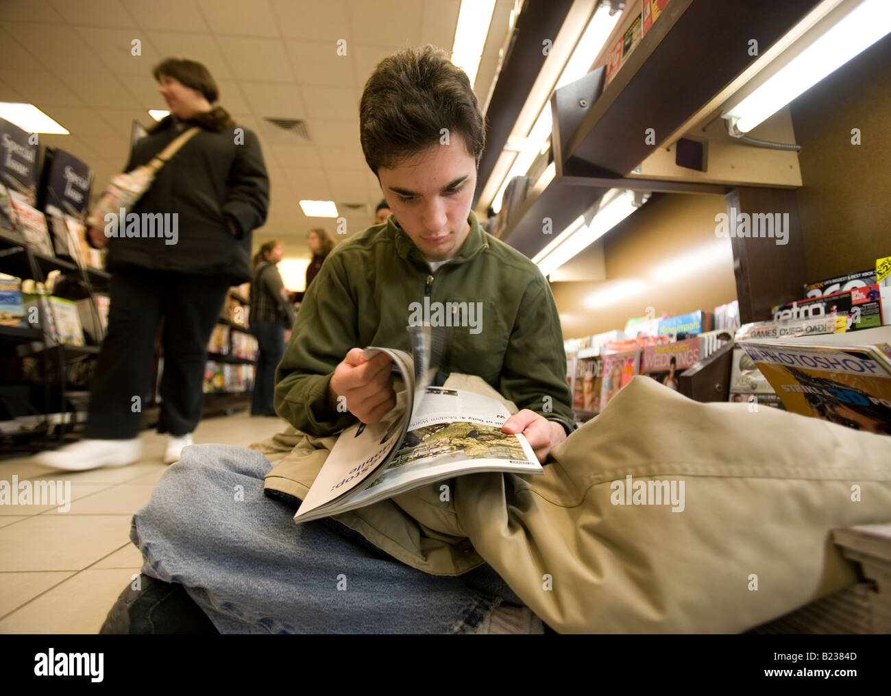 Young man reading magazine at magazine stand in book store Stock Photo ...