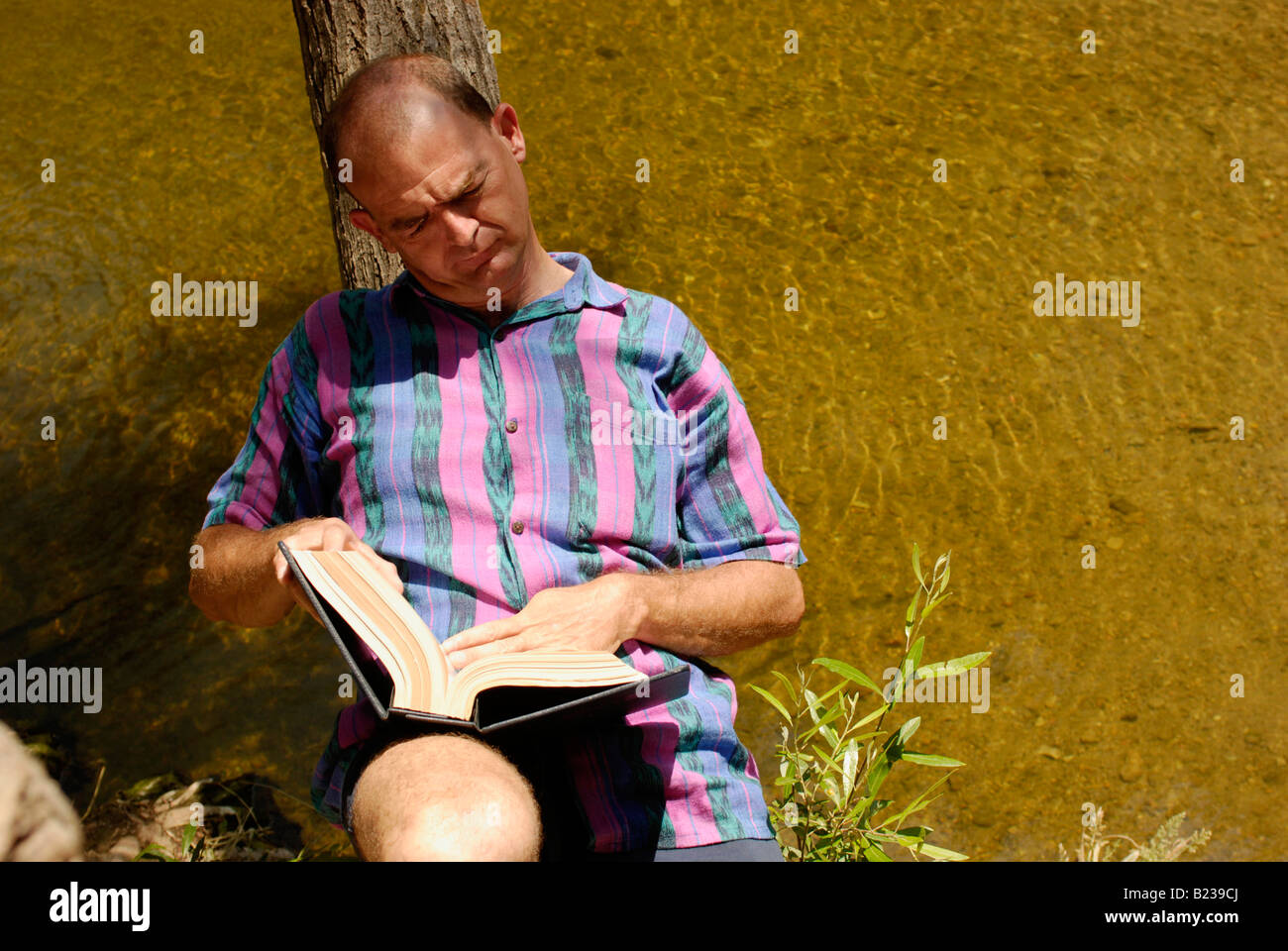 Confused man reading a book Stock Photo - Alamy