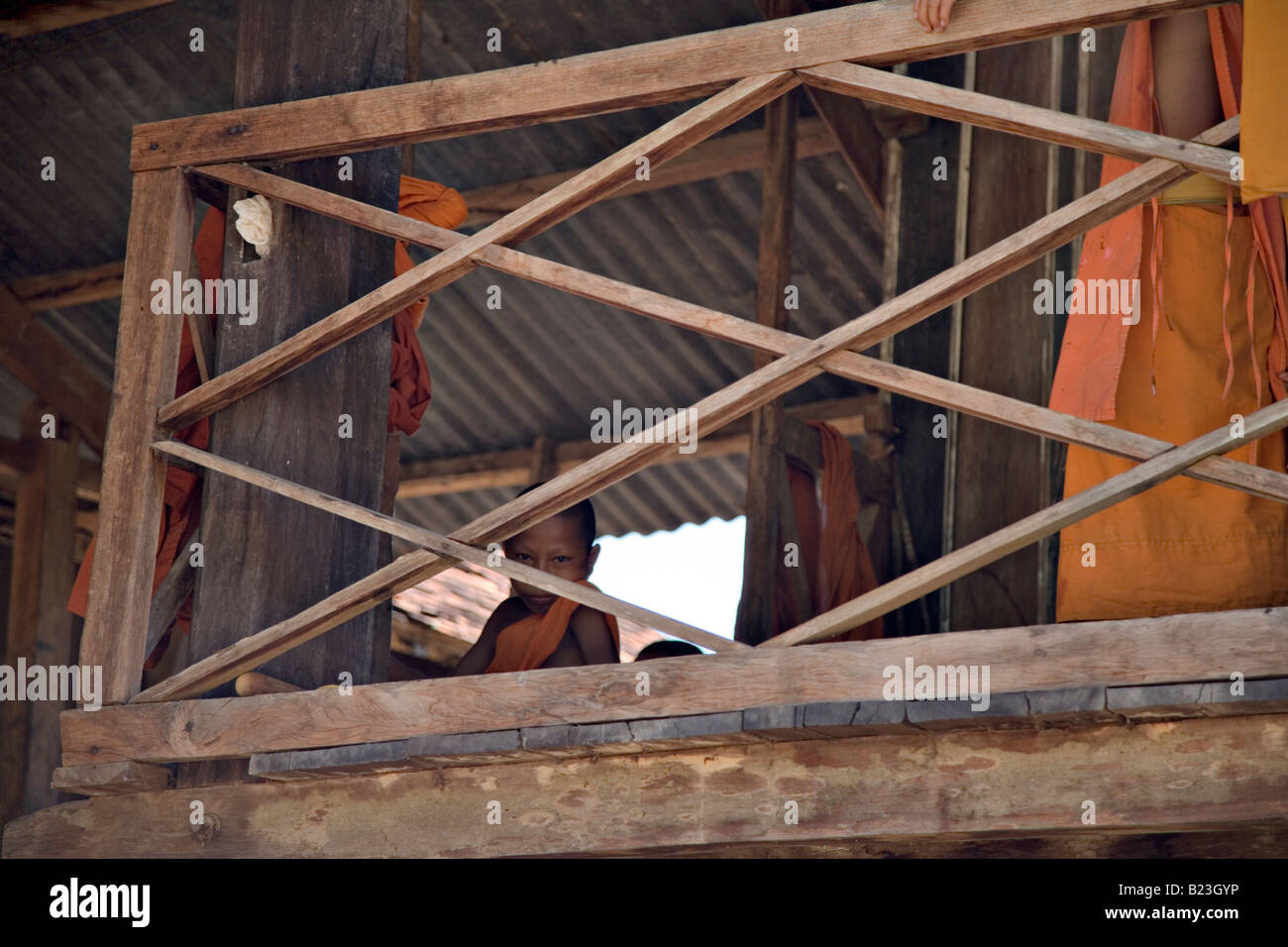 Young Buddhist monk peeks out from temple dormitory porch, southern ...