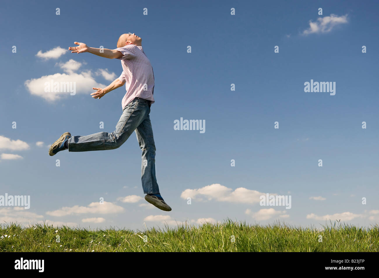 Young man is jumping over a green Stock Photo - Alamy