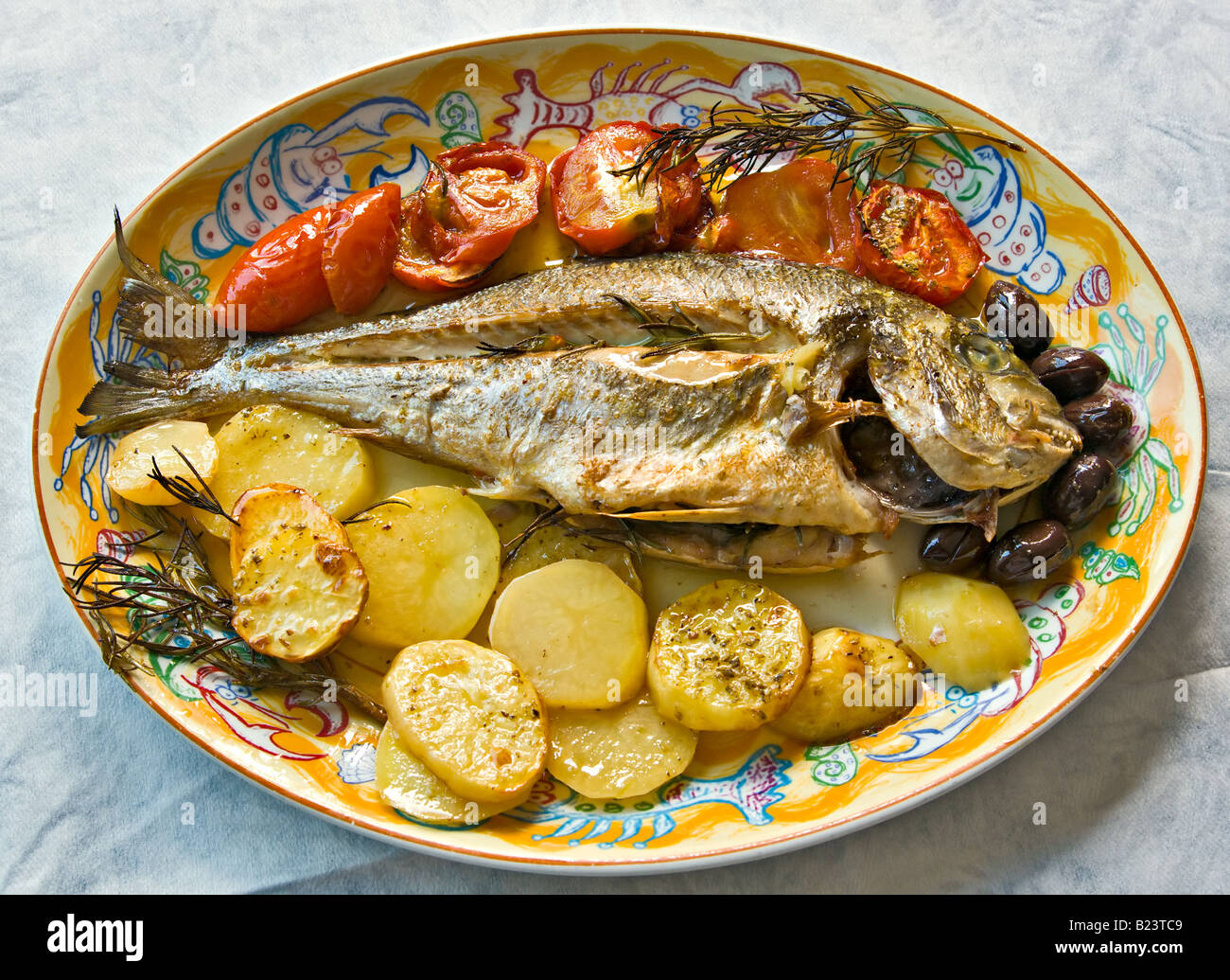 Fresh fish cooked in owen with potatoes tomatoes and olives Stock Photo ...