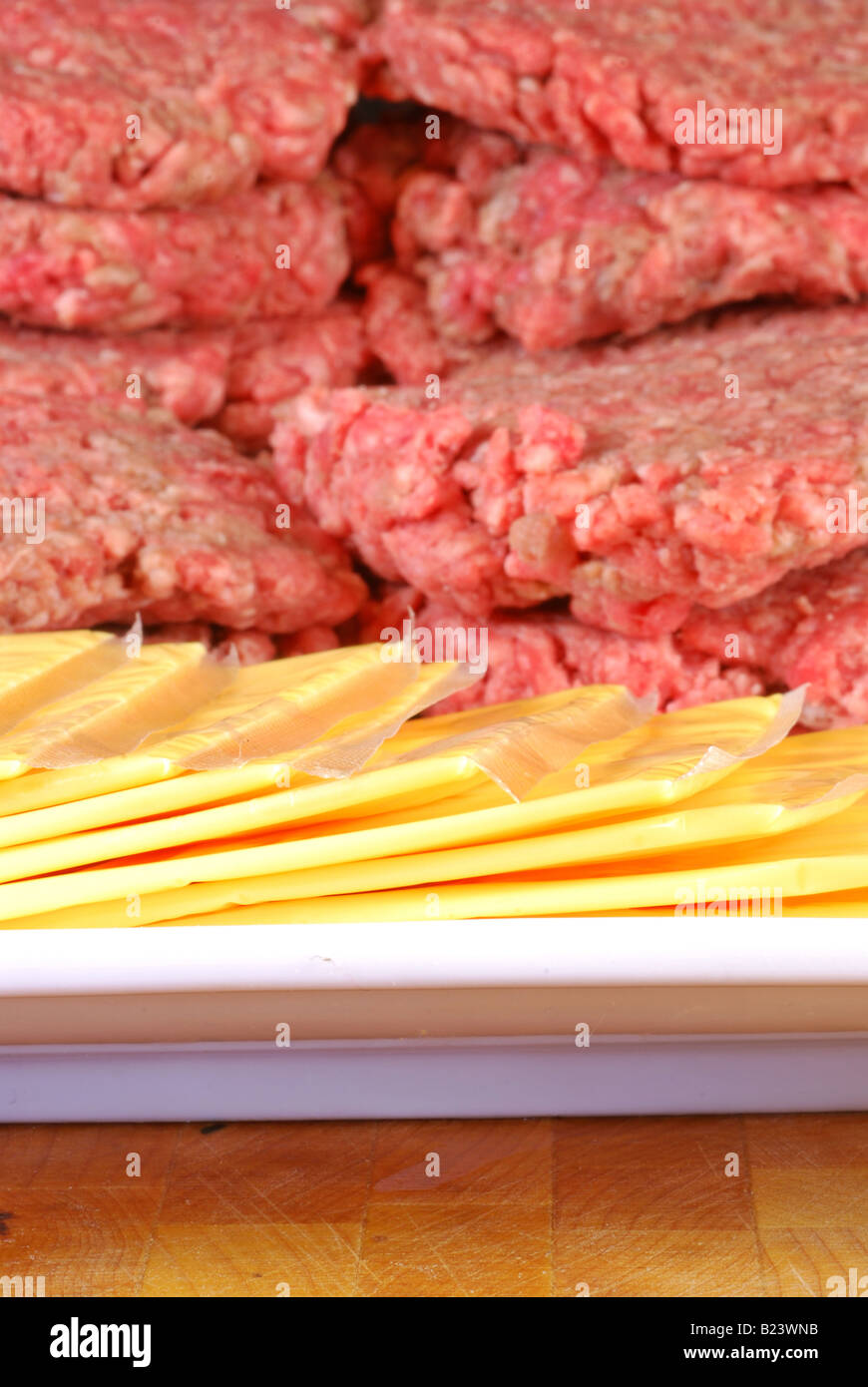Uncooked hamburger patties with slices of American cheese Stock Photo ...