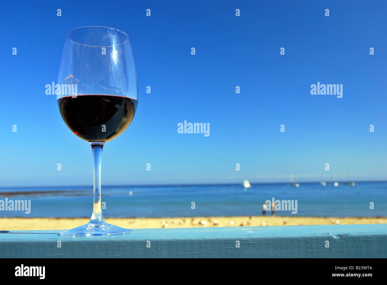 Glass of red wine on a restaurant s deck railing by the ocean beach ...