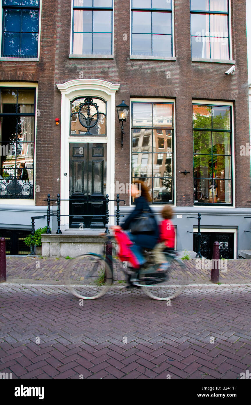 Dutch mother and child riding typical bicycle on canal street in front ...