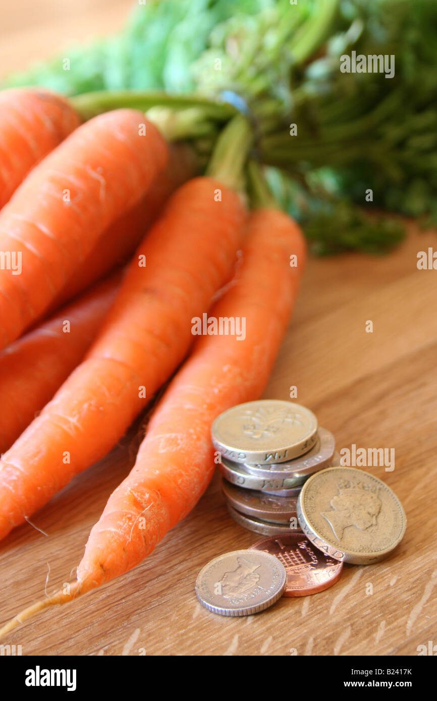 A bunch of carrots on a tabletop with a pile of coins, illustrating the ...