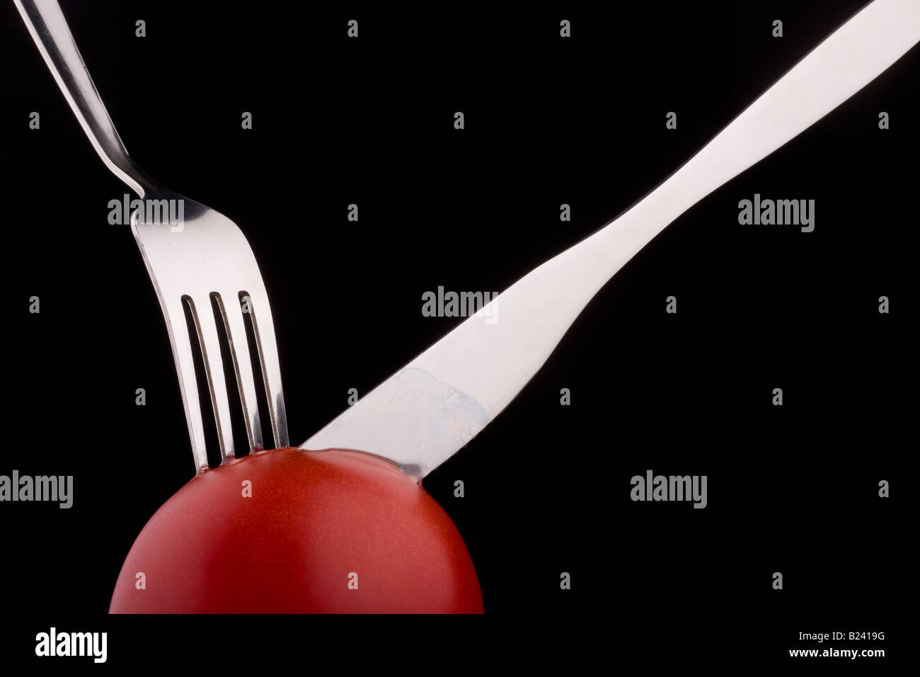 Knife with forks help slices juicy tomato Stock Photo - Alamy