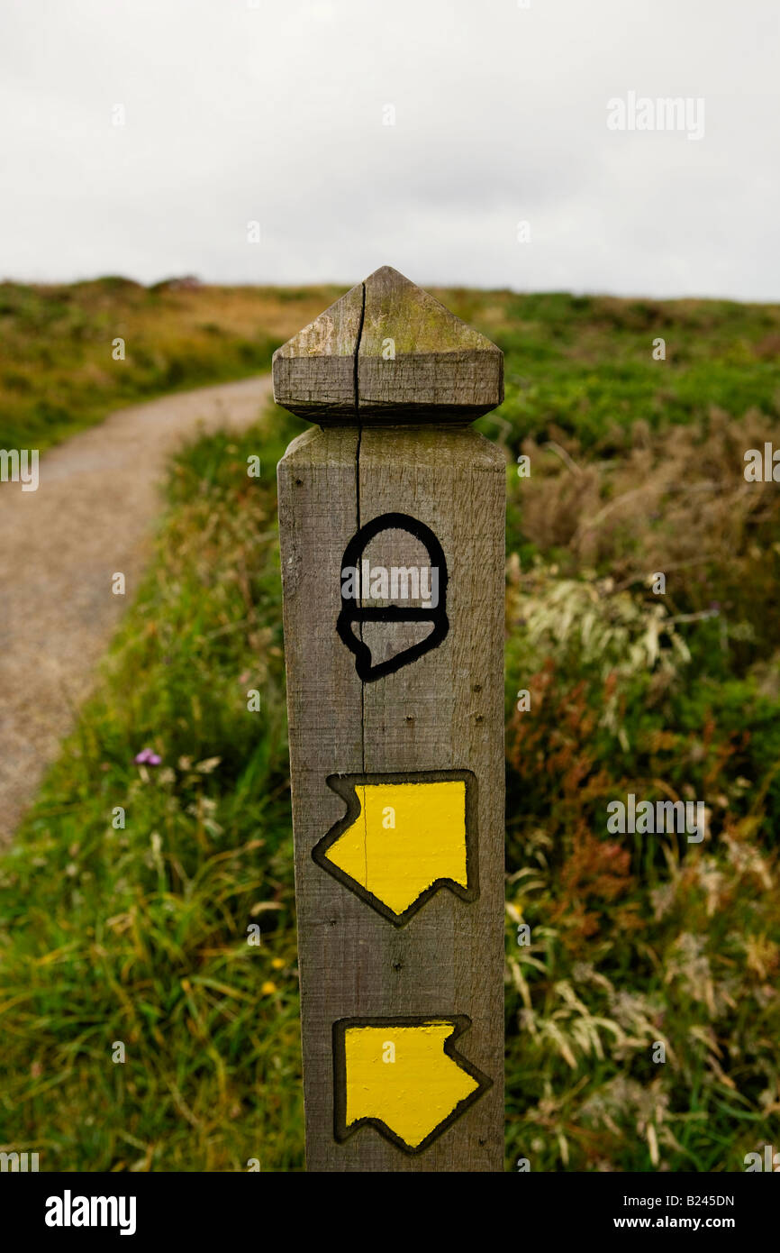 A wooden South West (Cornish) Coastal Path direction post with yellow ...