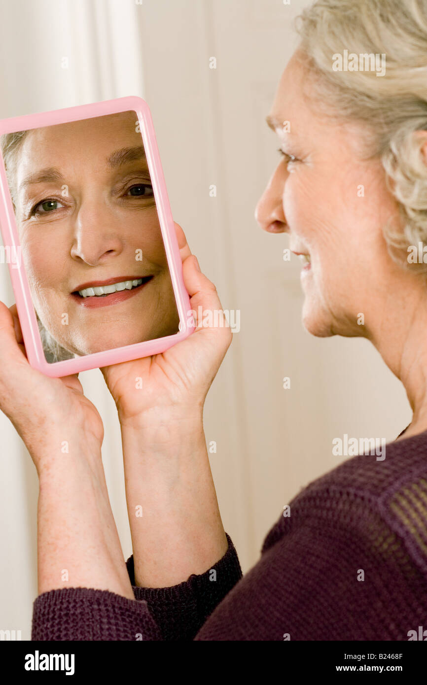 A senior woman looking in a mirror Stock Photo - Alamy