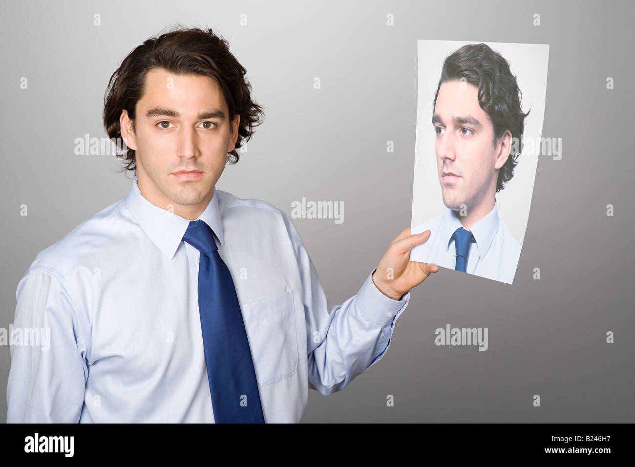 Portrait of a man holding a photograph of himself Stock Photo - Alamy