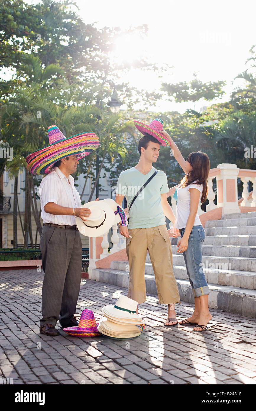 Couple and man selling hats Stock Photo - Alamy