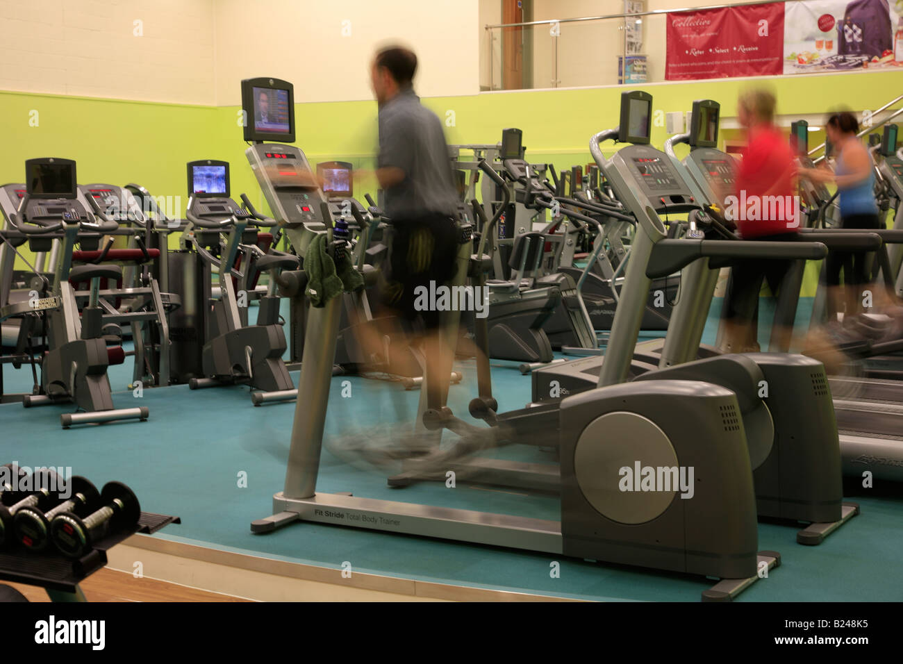 People at the gym on running machines, blurred for speed and power ...