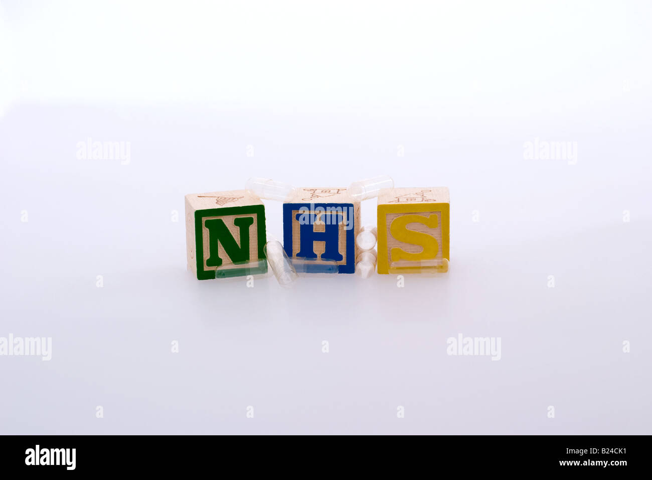 Three children's blocks spellling NHS with empty medicine capsules ...