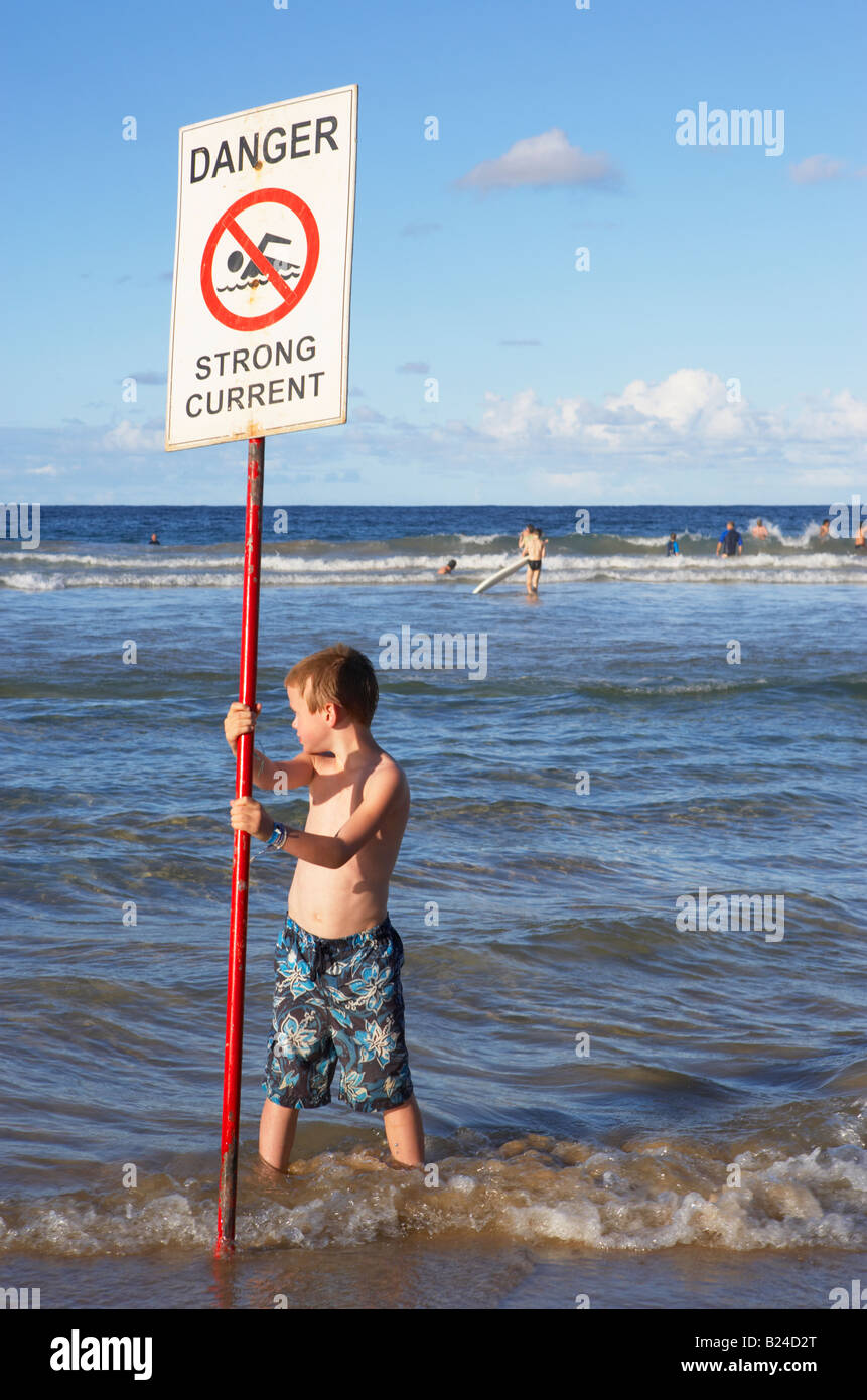 Boy holding a strong currents warning sign Manly beach Sydney Australia ...